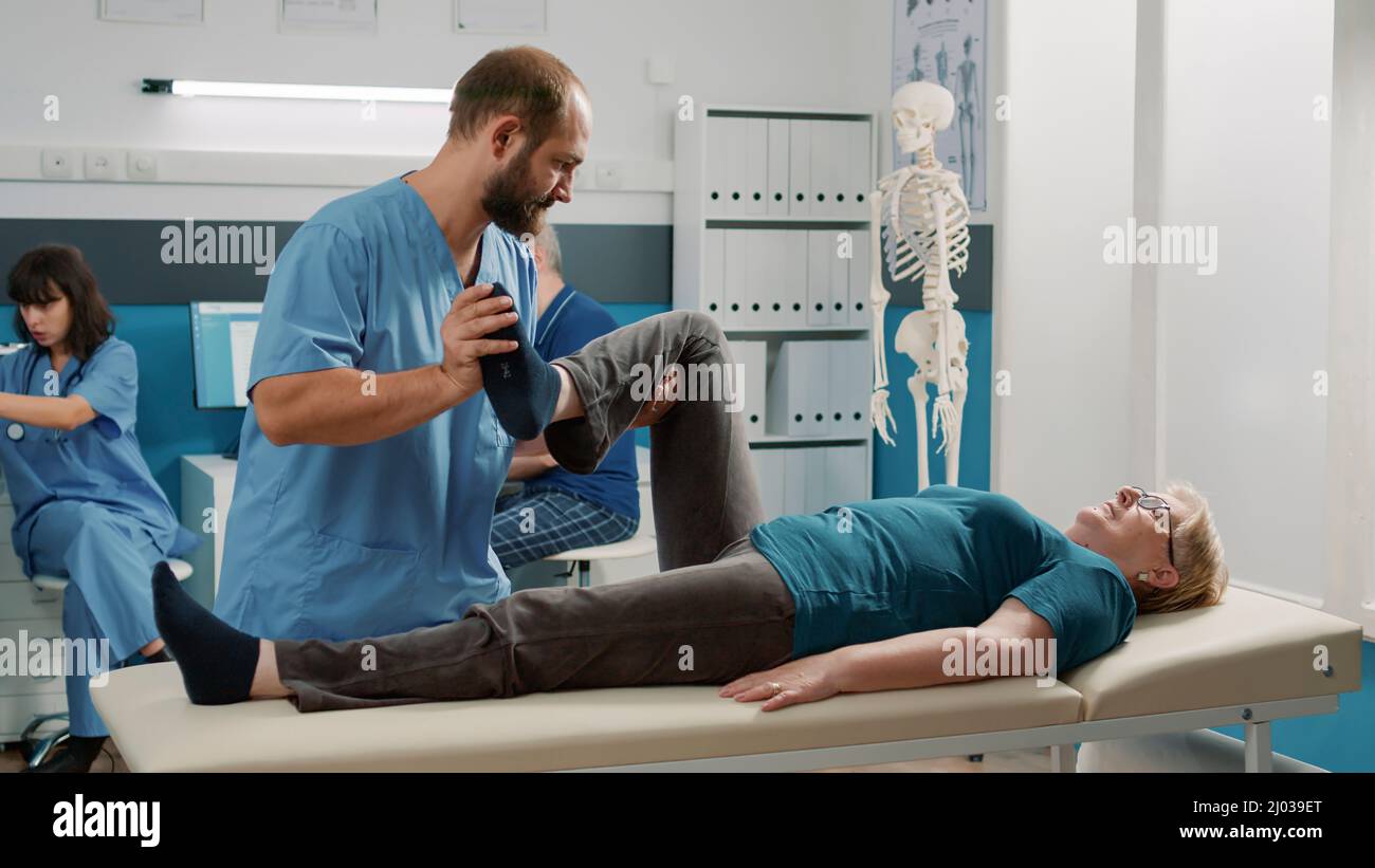 Male physician doing legs raise procedure with senior patient in ...