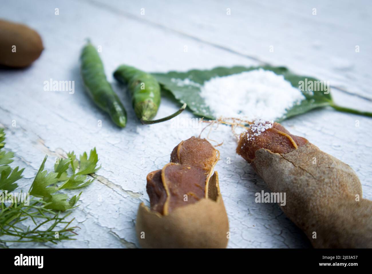 Some raw tamarind with tamarind leaf in a wooden bench with sunlight ...