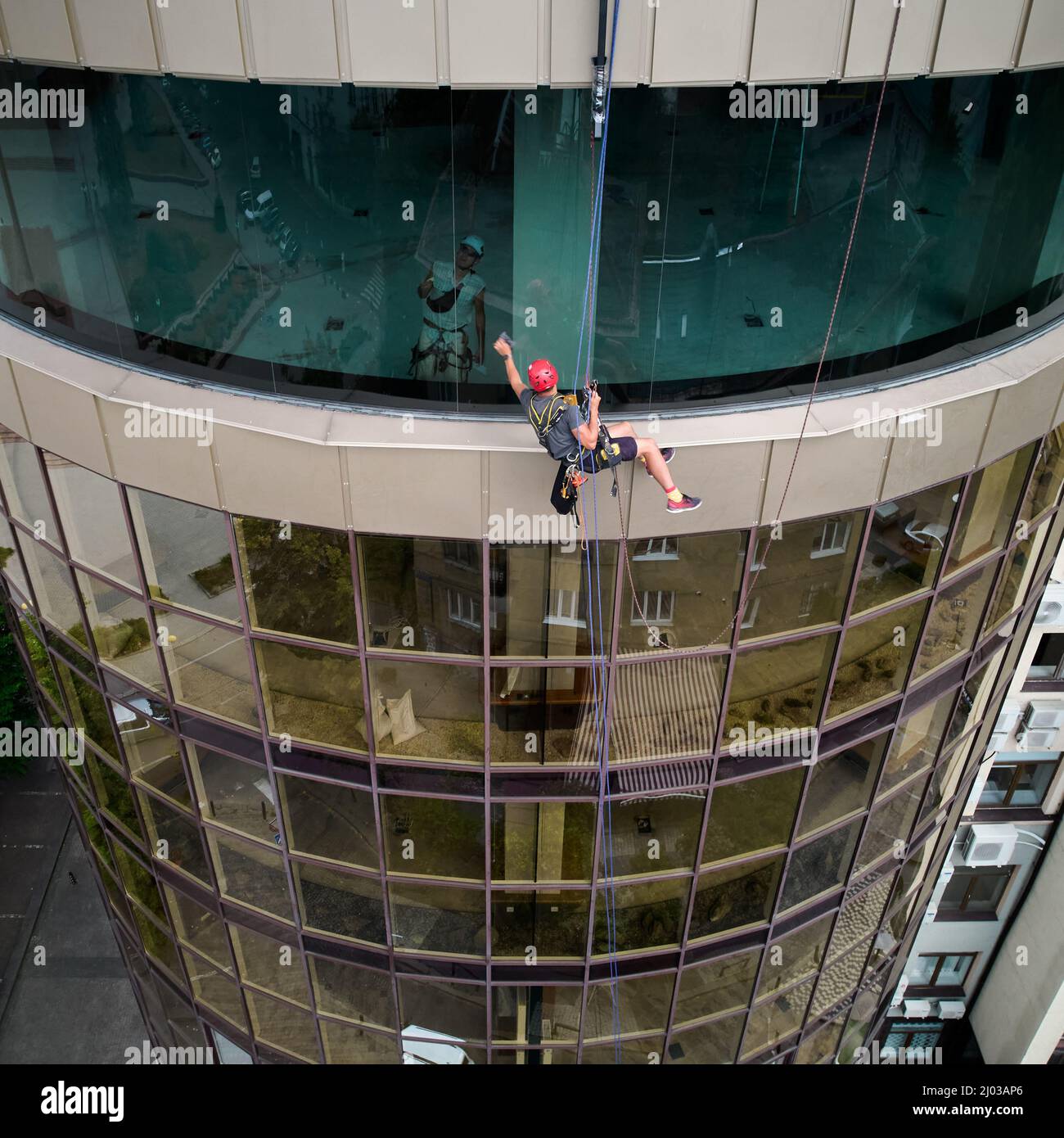 Industrial mountaineering worker hanging on climbing rope and cleaning ...