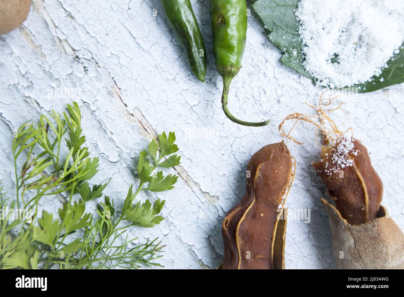 Some raw tamarind with tamarind leaf in a wooden bench with sunlight ...