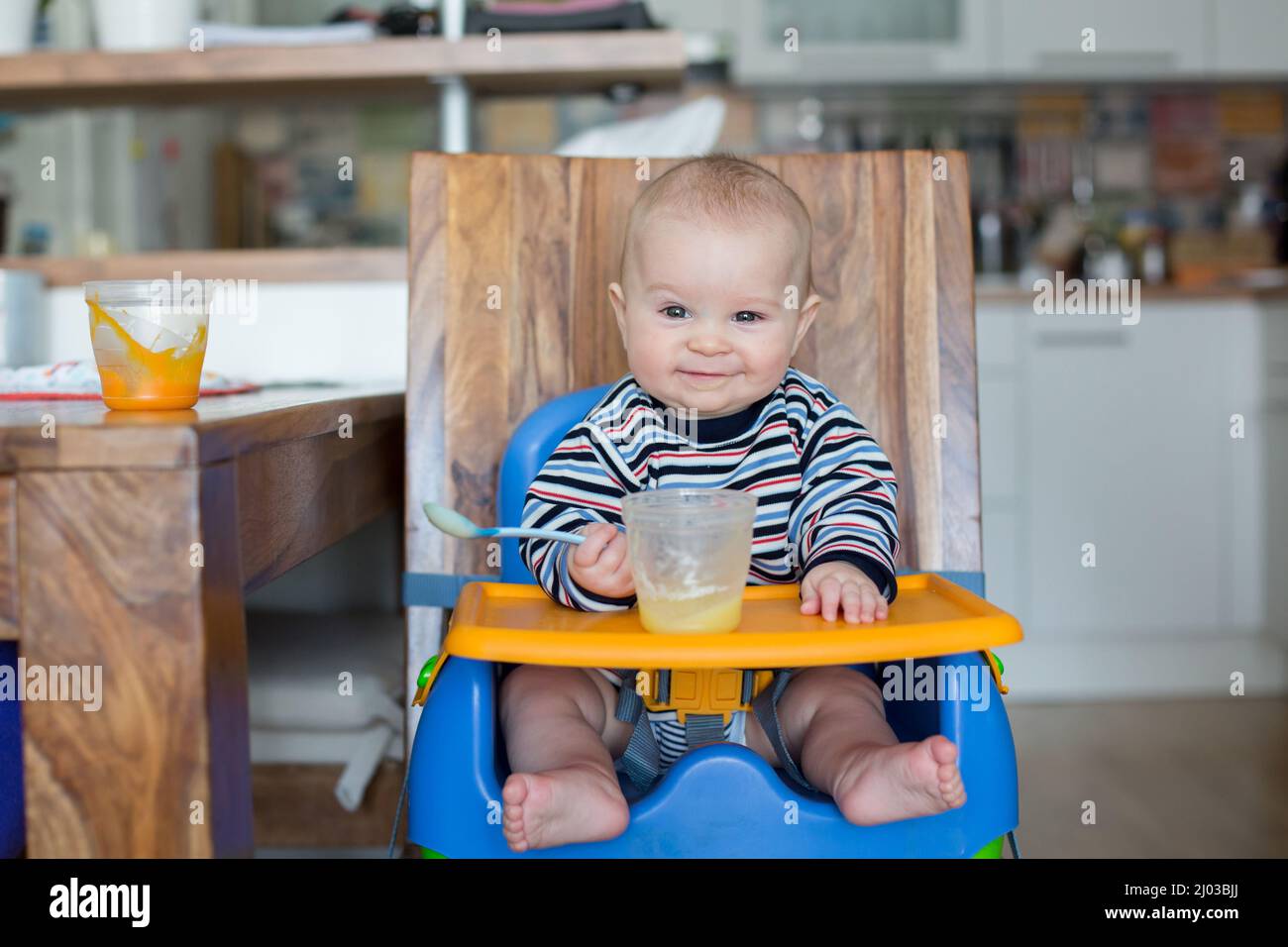 Little baby boy, eating mashed food for the first time in his life ...