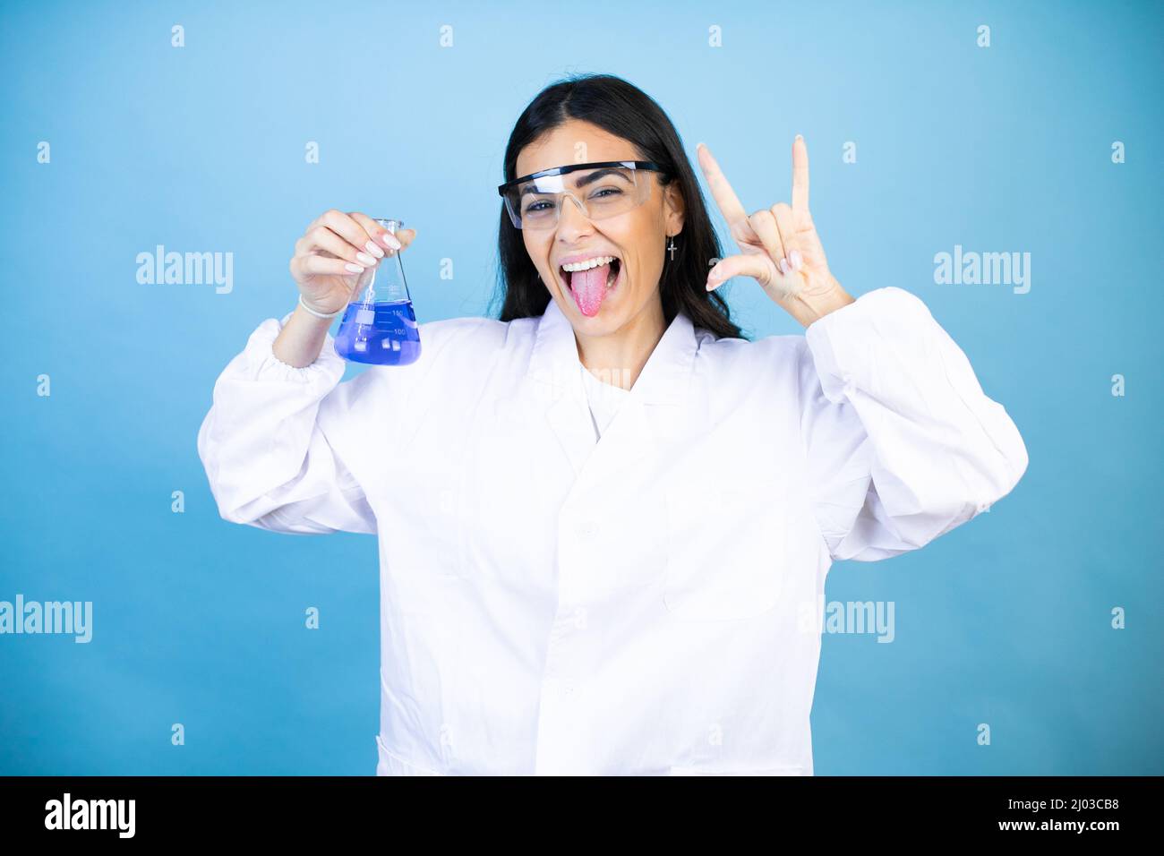 Young brunette woman wearing scientist uniform holding test tube over ...