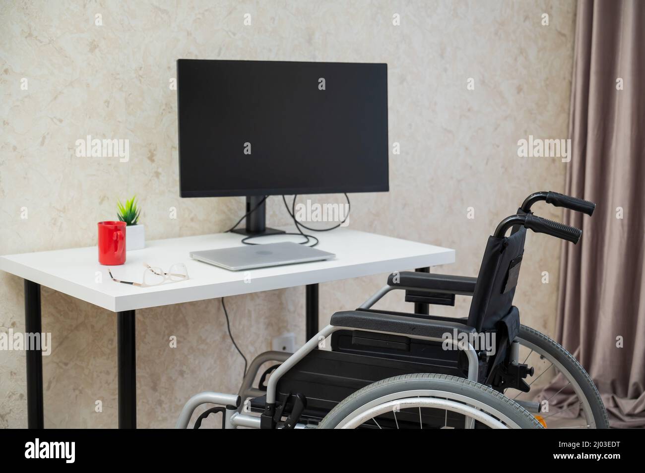 Workplace for a disabled person. Wheelchair at the table with a ...