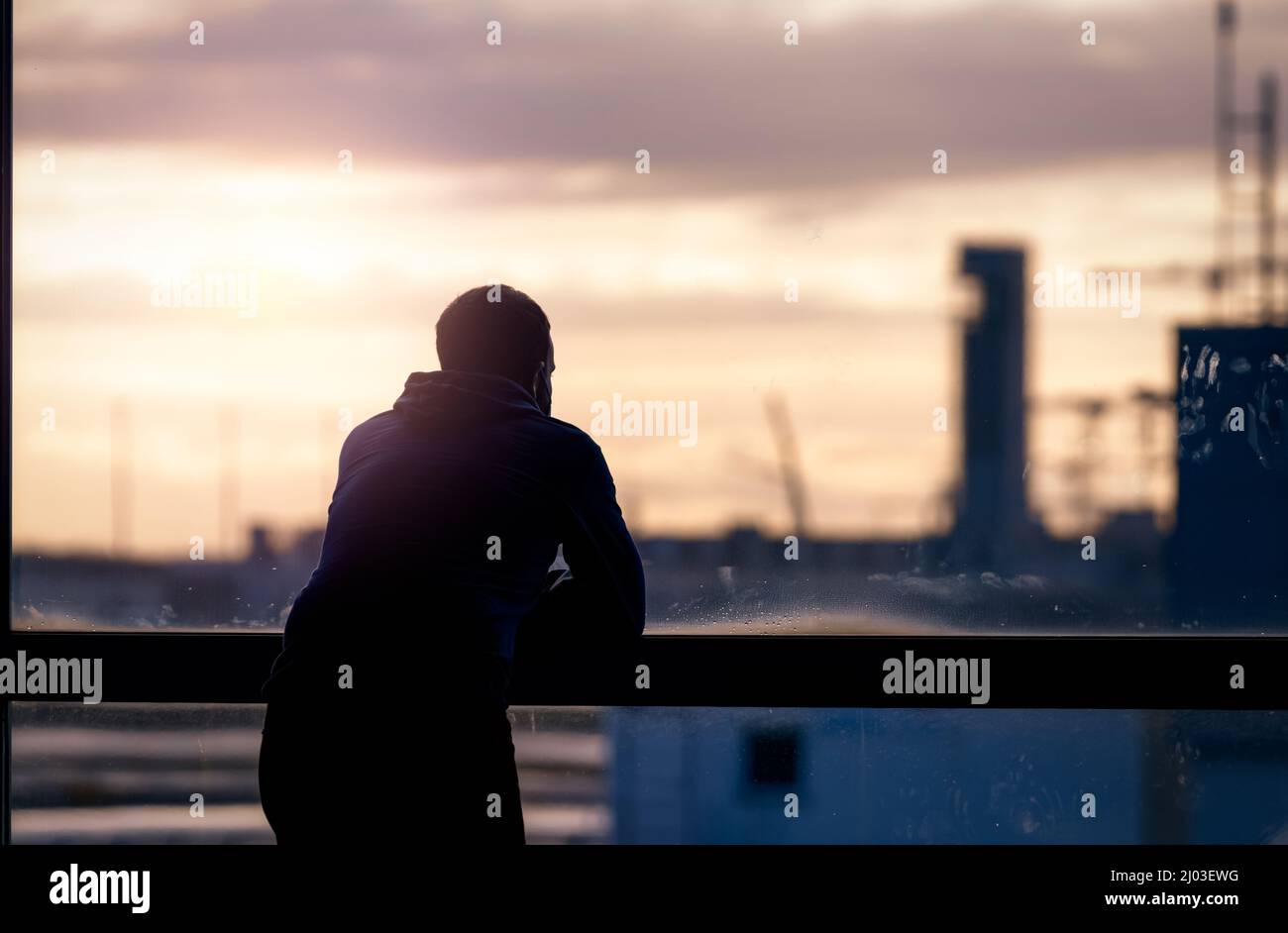Back view of a man standing and looking through glass window of the ...