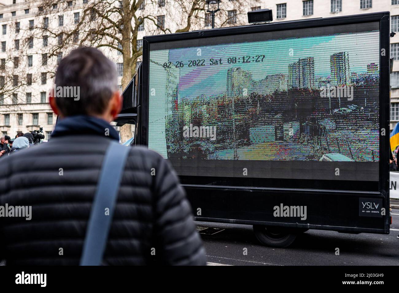 A passer-by views scenes of destruction on a screen at protests at ...