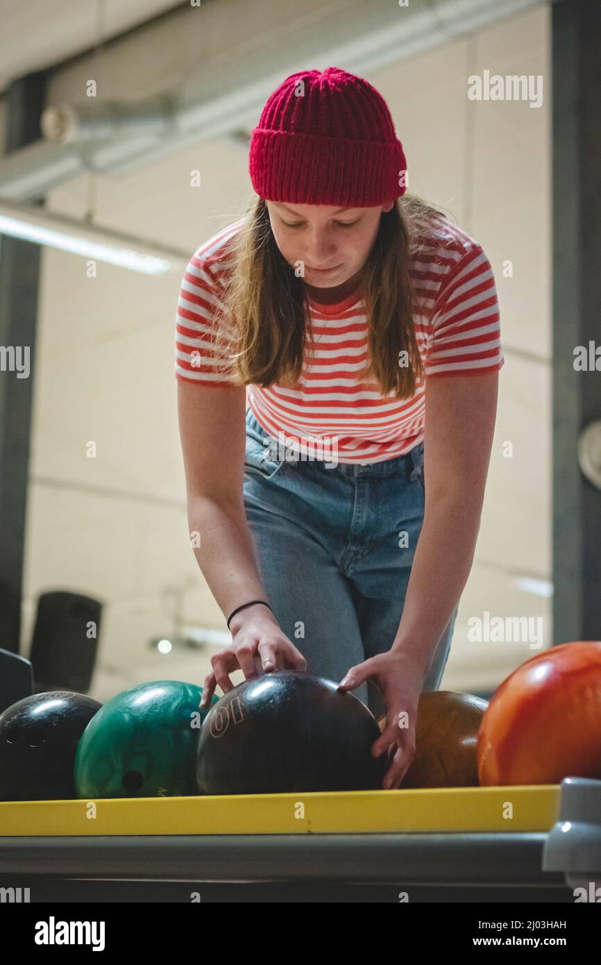 young amateur female bowler wearing a red cap and a spotted t-shirt ...