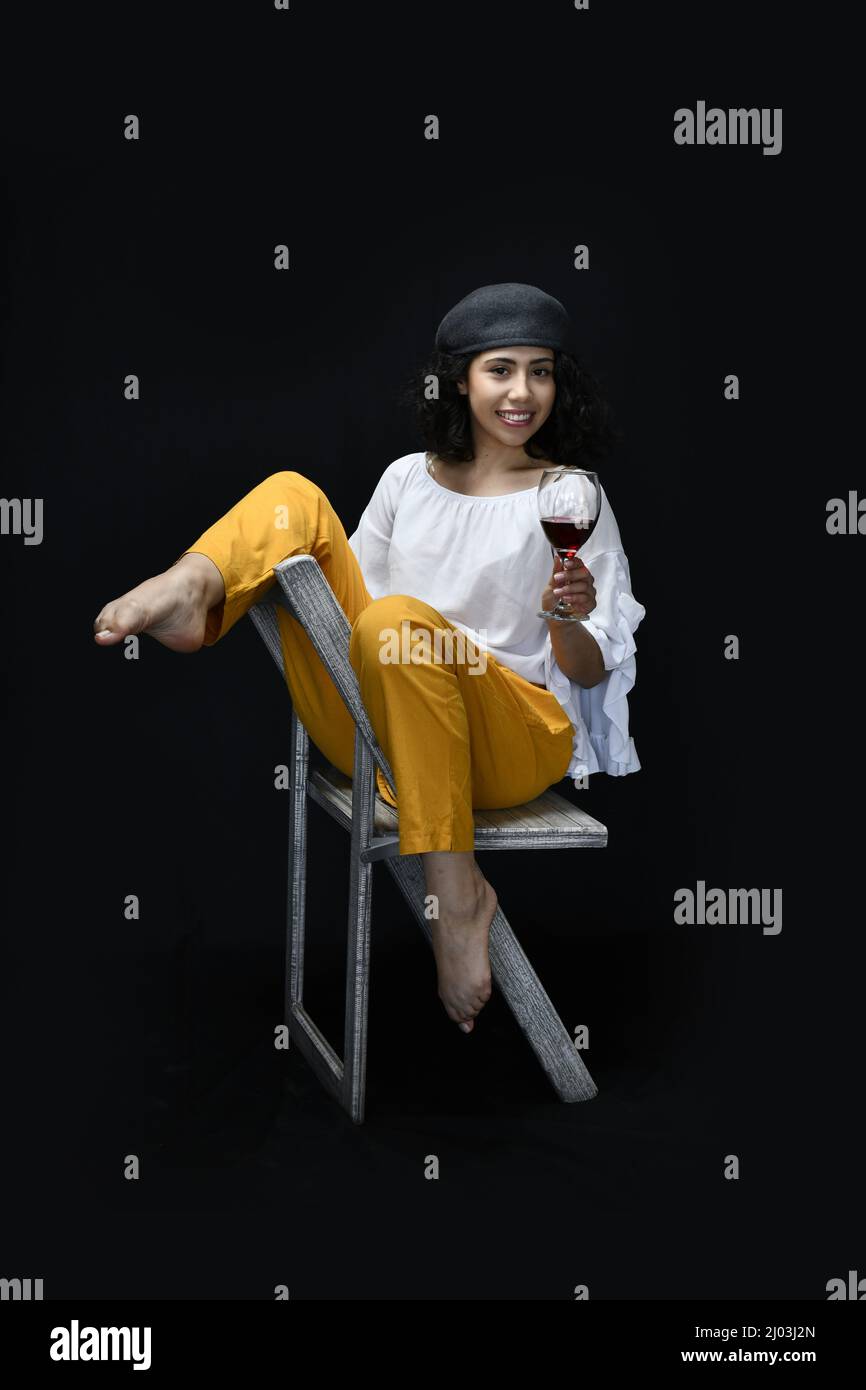 Vertical shot of a Hispanic woman, sitting opposite on a chair with one ...