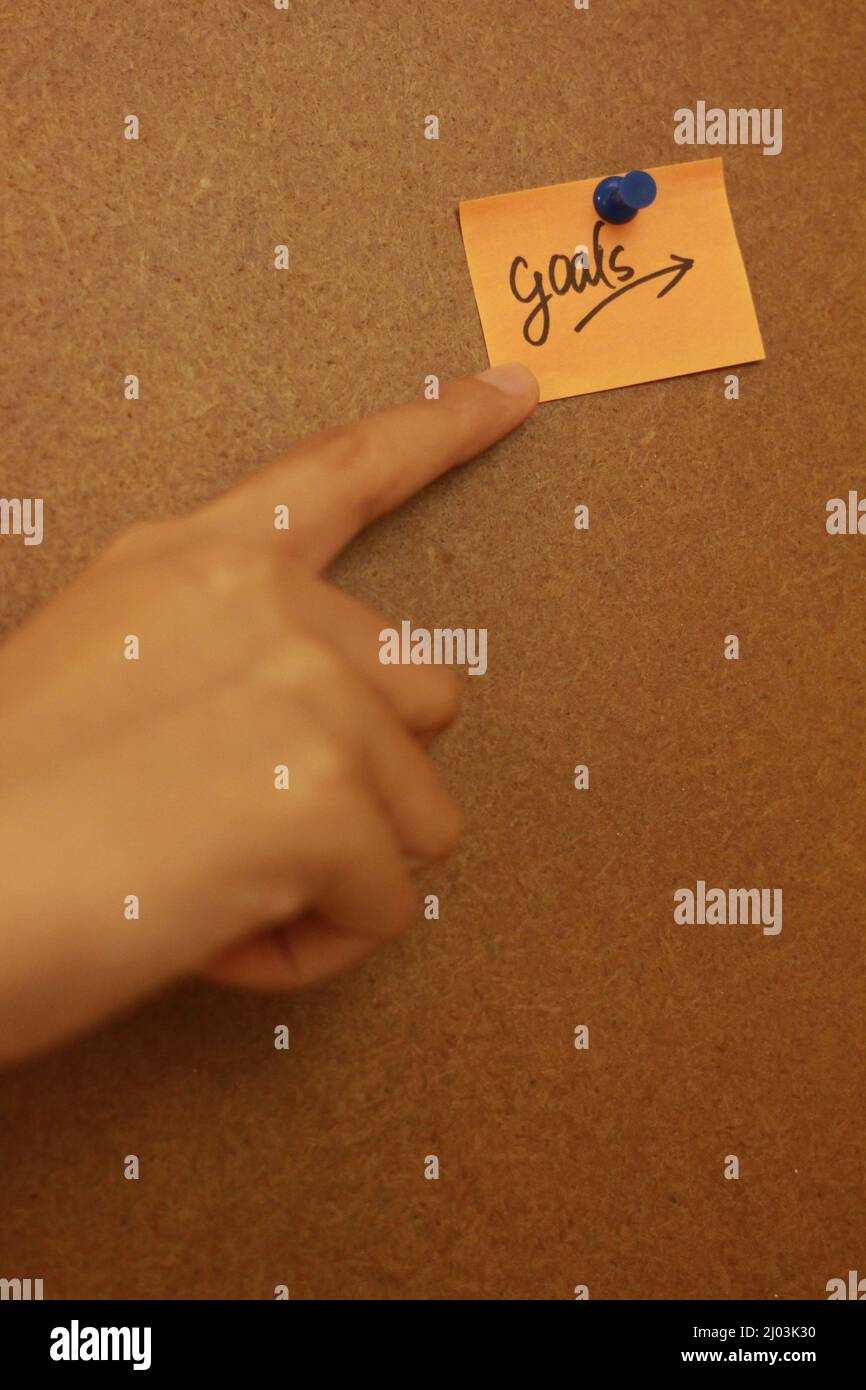 Goals text written on sticky note concept designed with woman hand ...