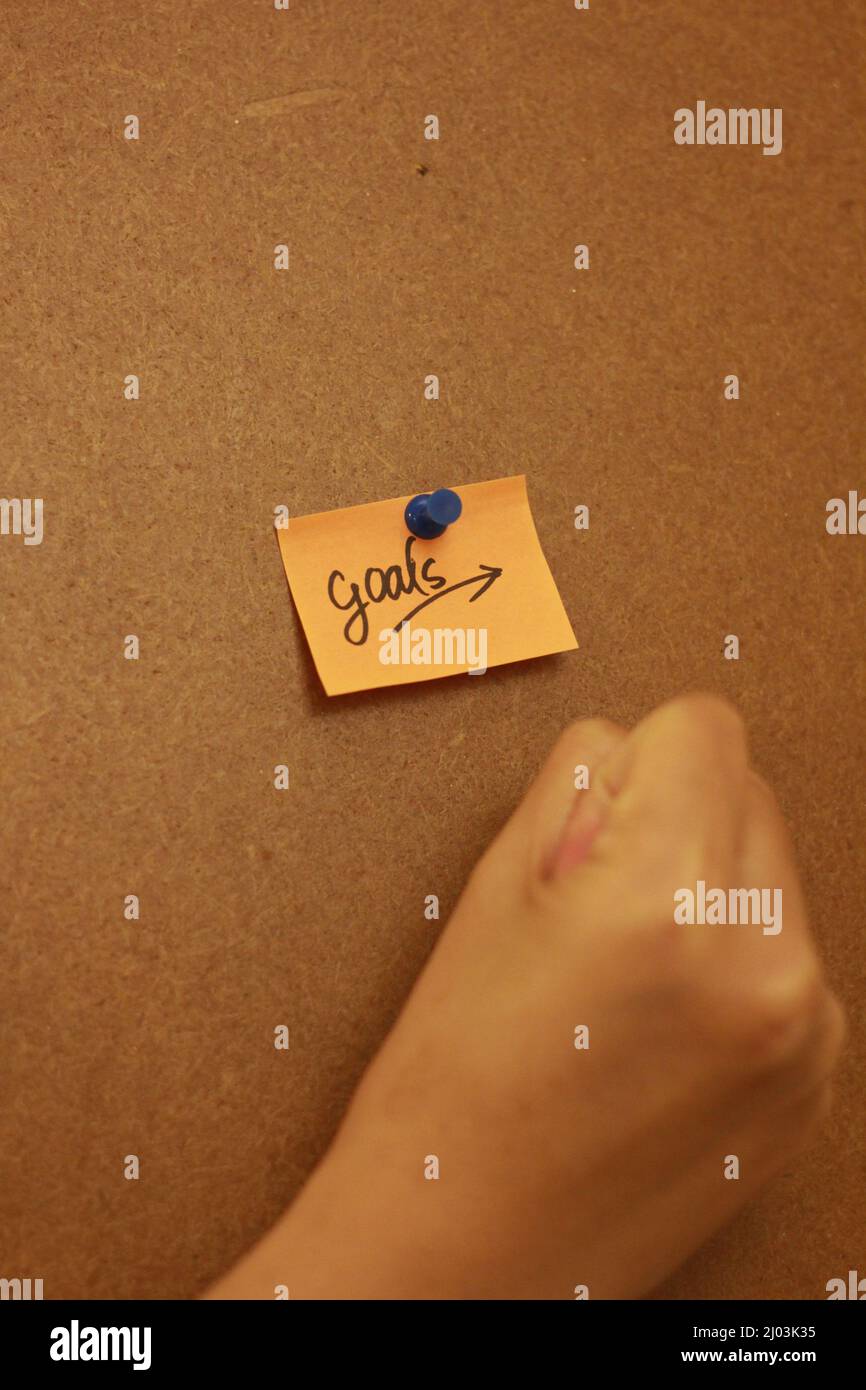 Goals text written on sticky note concept designed with woman hand ...