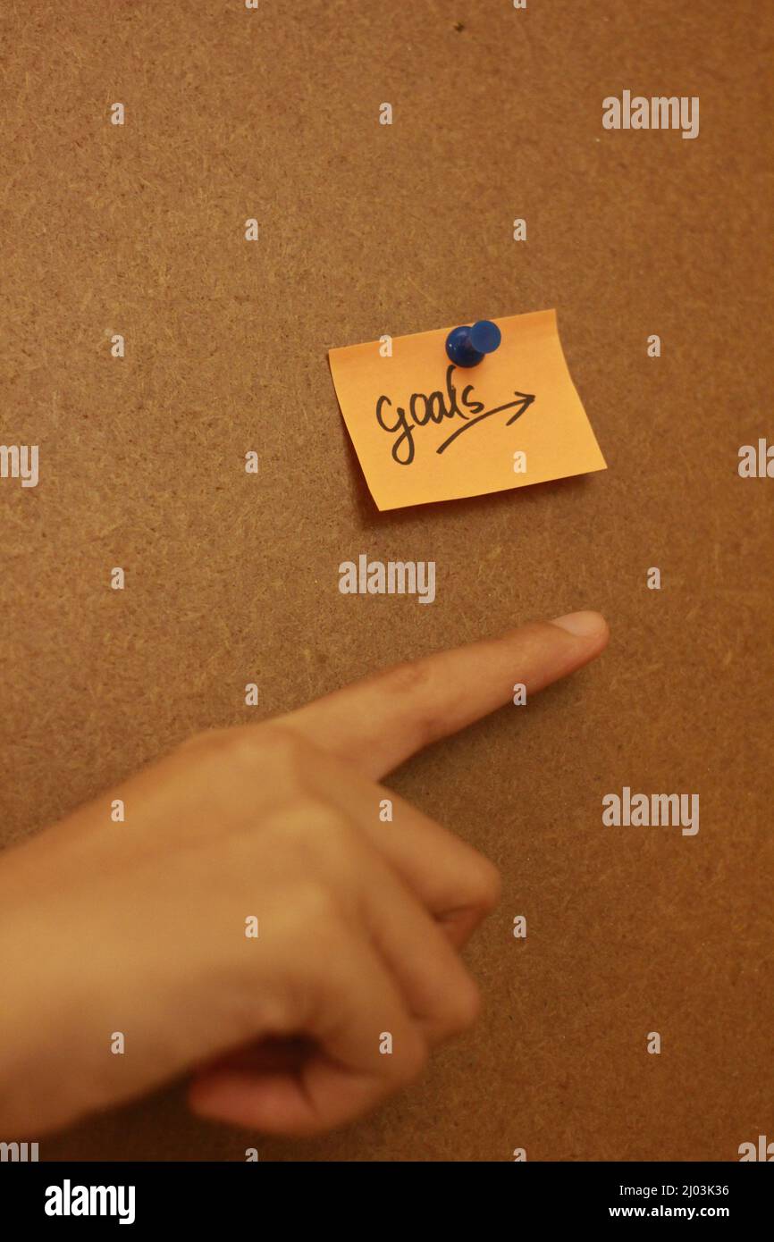 Goals text written on sticky note concept designed with woman hand ...
