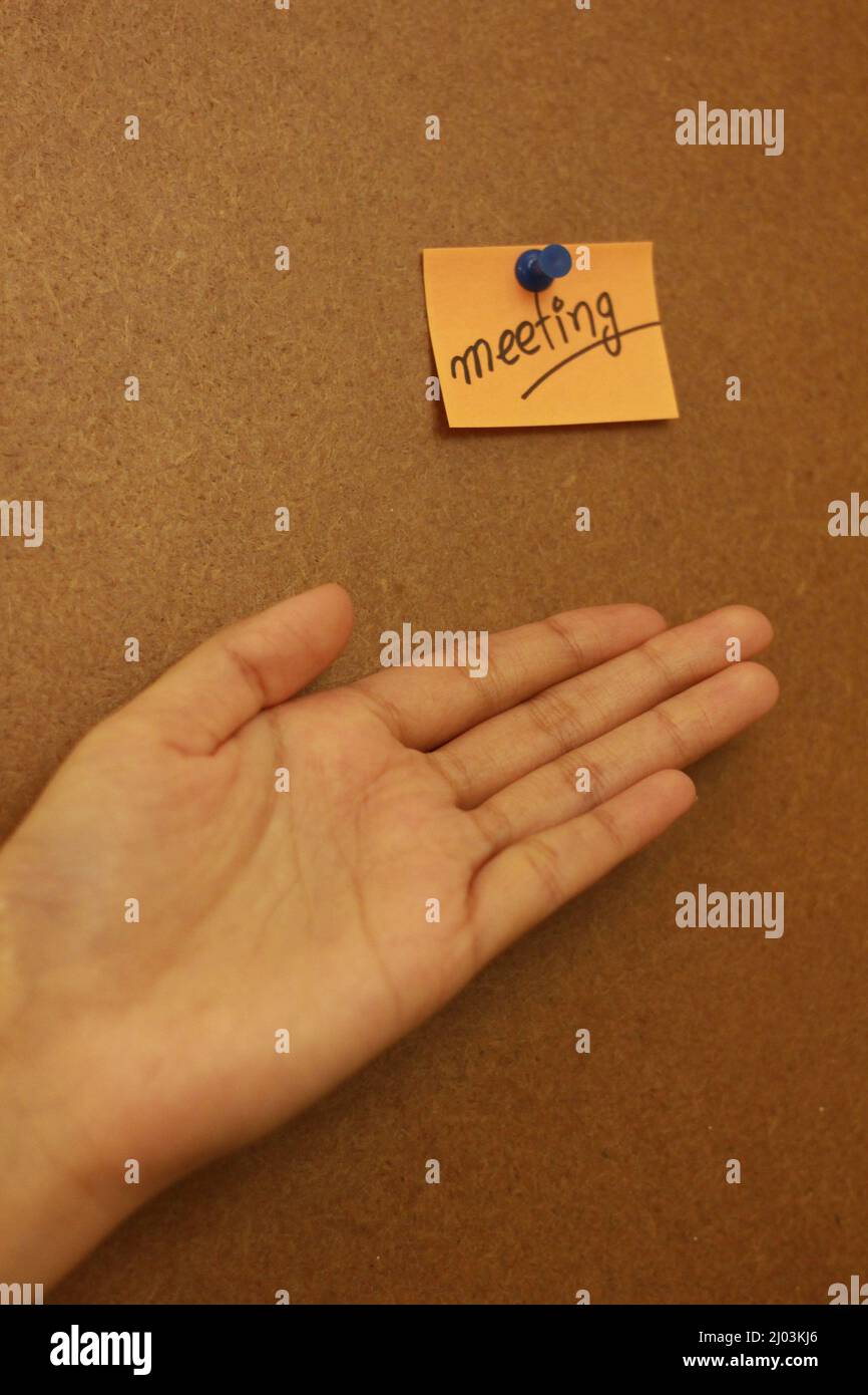 Meeting written on sticky note concept designed with woman hand Stock ...