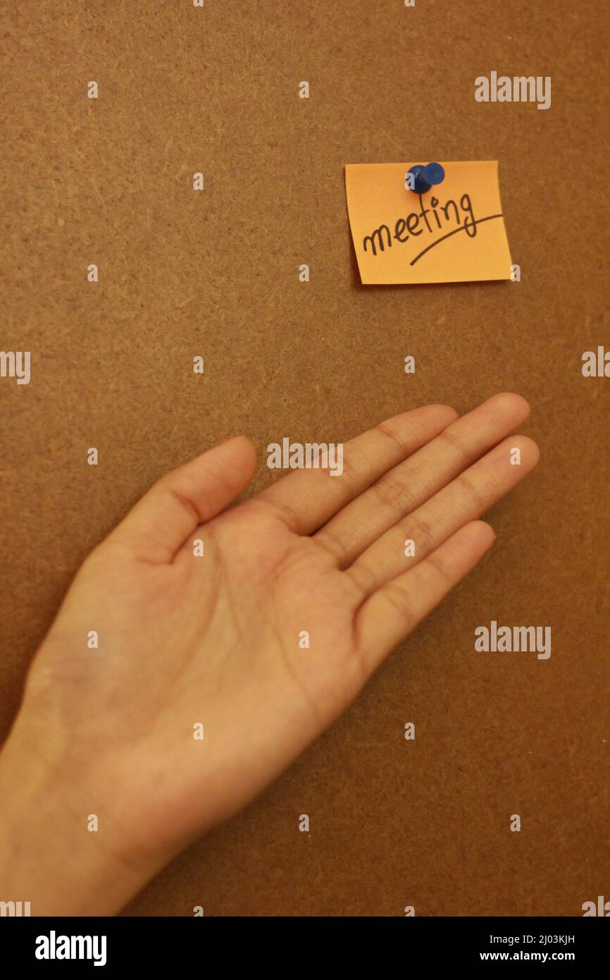 Meeting written on sticky note concept designed with woman hand Stock ...