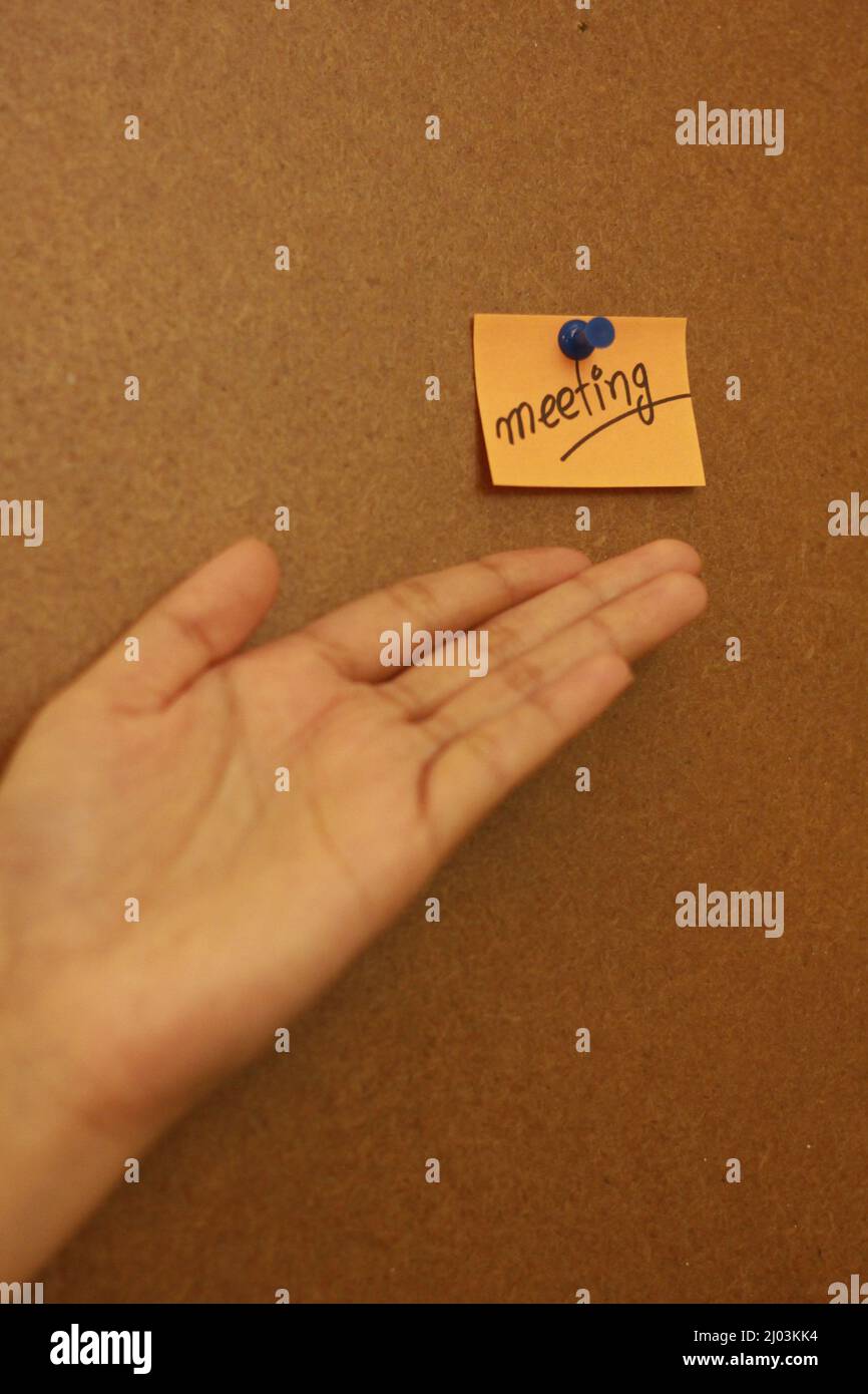 Meeting written on sticky note concept designed with woman hand Stock ...