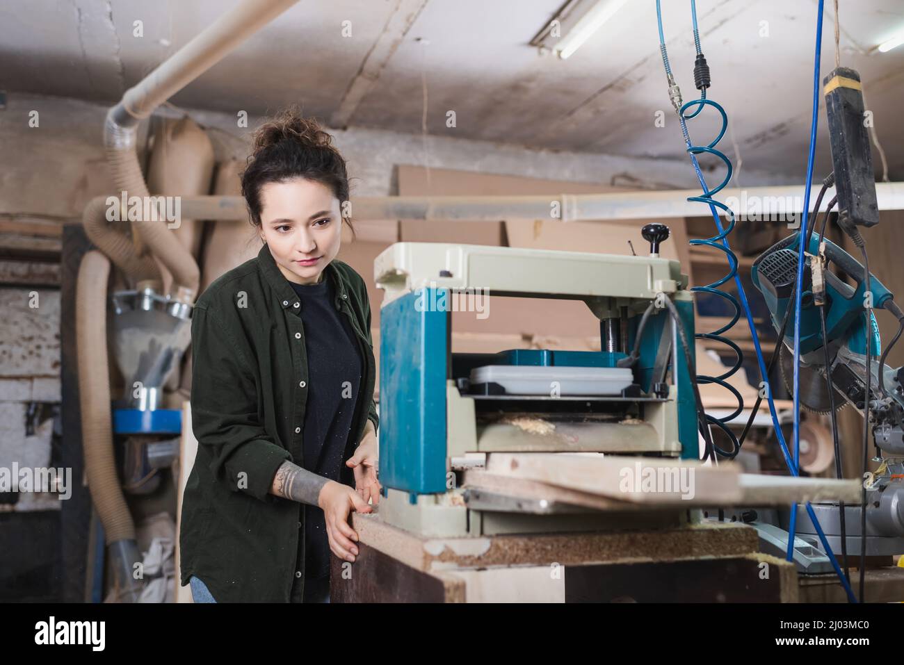 Brunette woodworker standing near thickness planer in workshop Stock ...