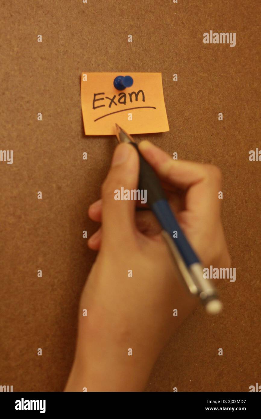 Exam text written on sticky note concept designed with woman hand Stock ...