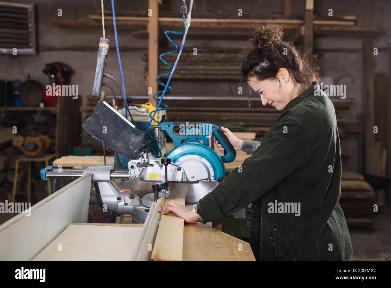 Side view of smiling carpenter using miter saw in workshop Stock Photo ...