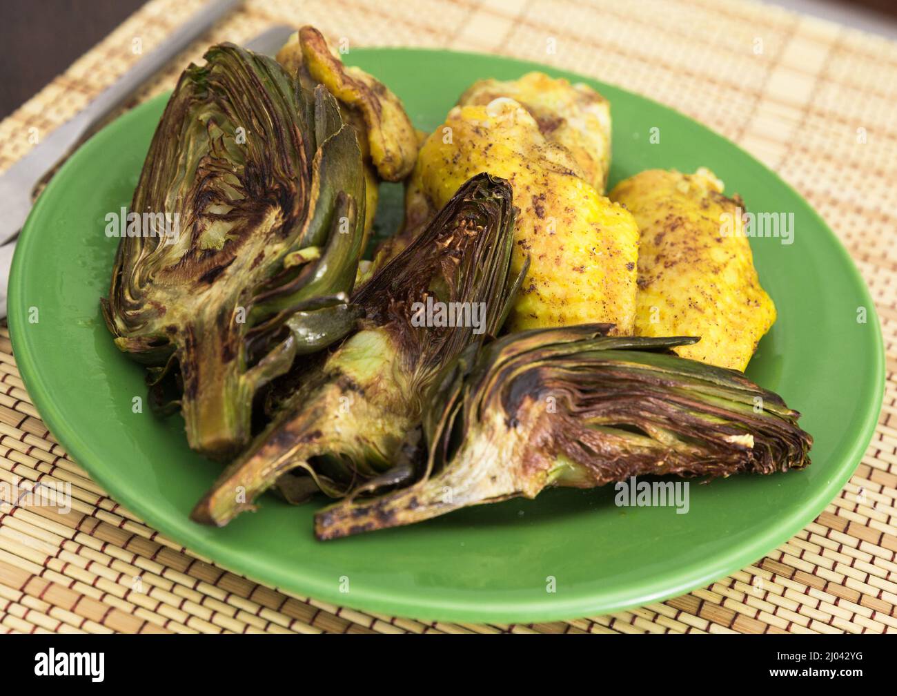 cooked fried chicken wings and halves artichokes on green plate Stock ...