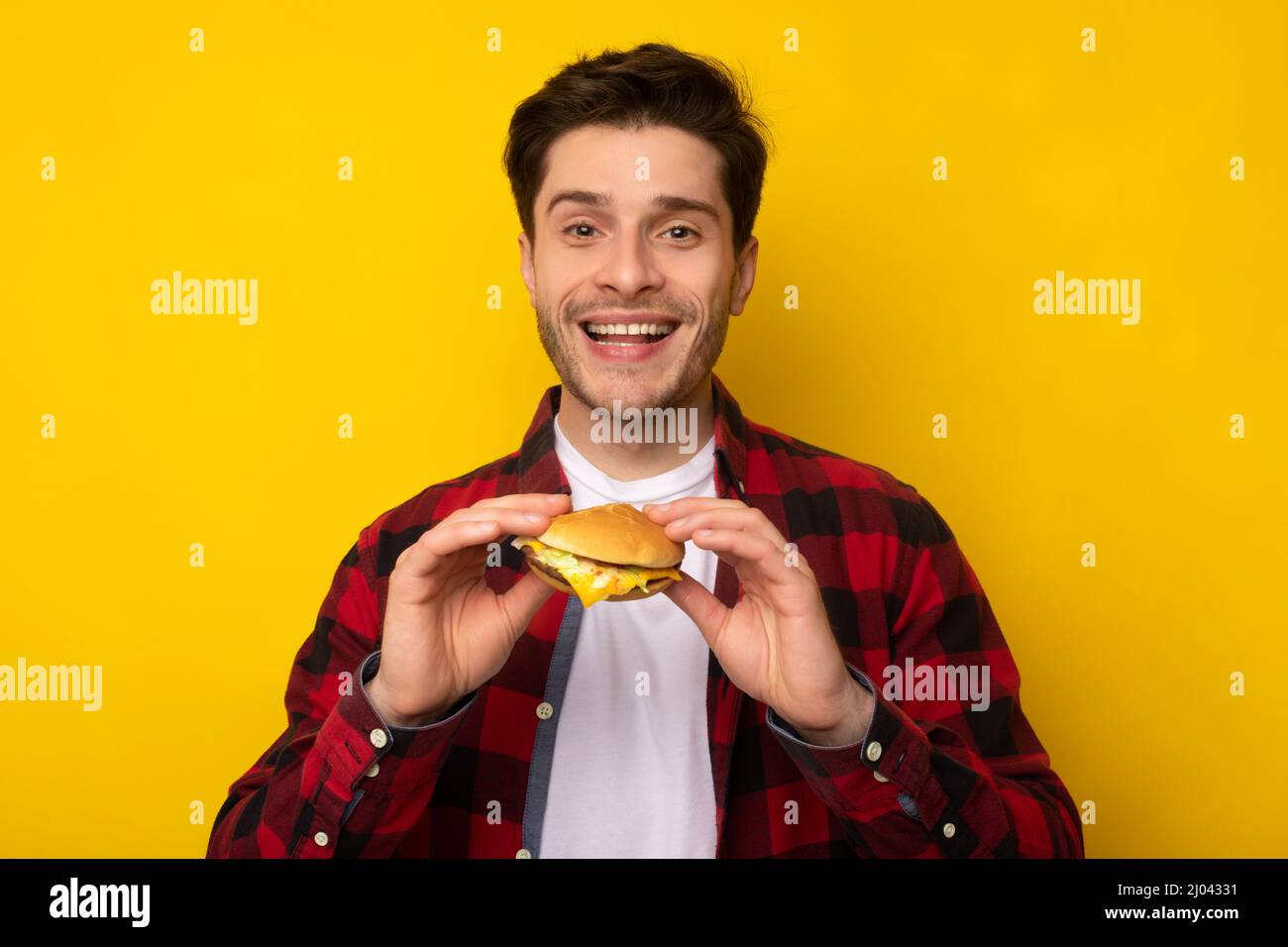 Smiling Young Guy Holding Burger At Studio Stock Photo - Alamy