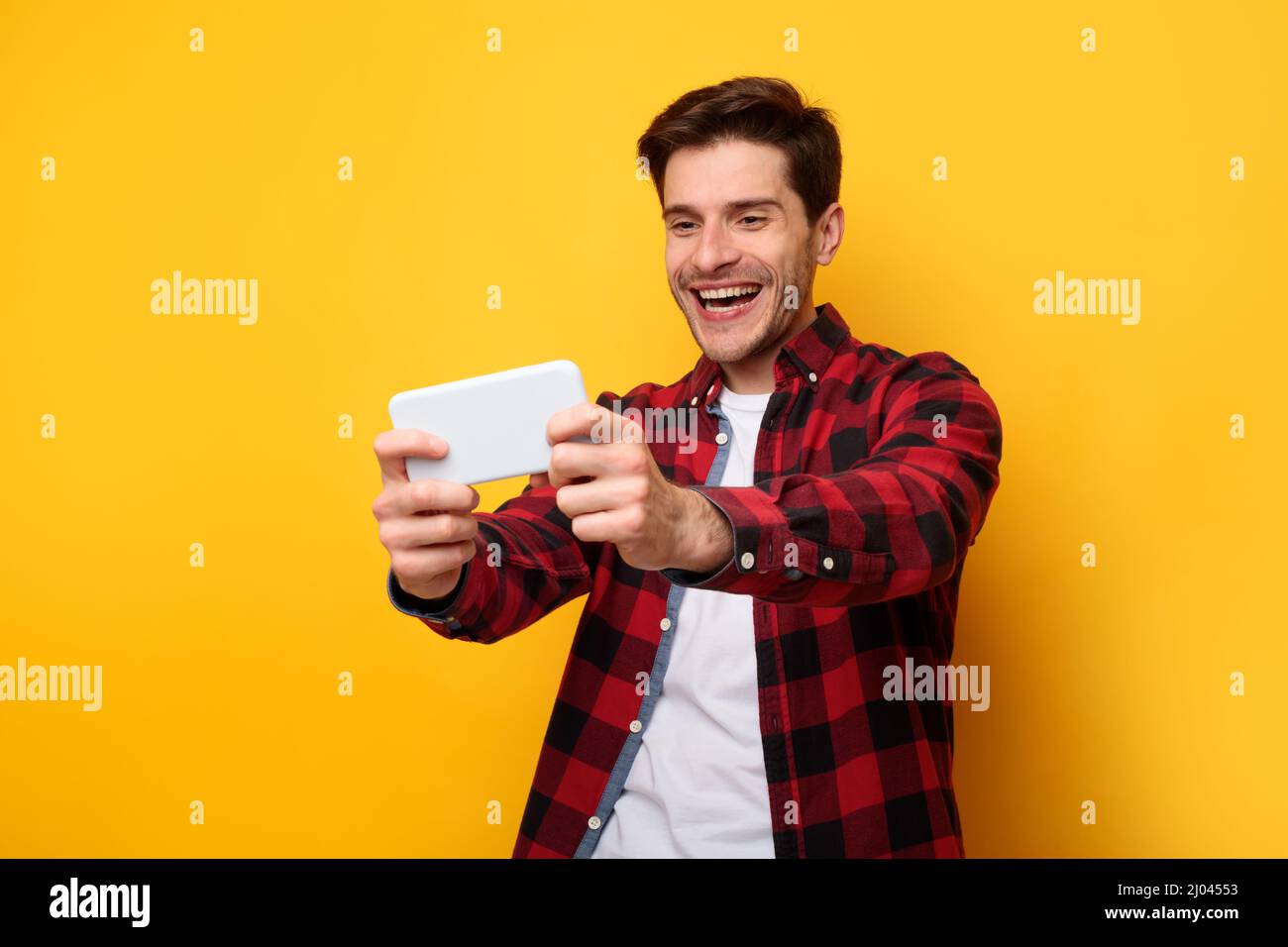 Excited man playing mobile games on yellow studio background Stock ...