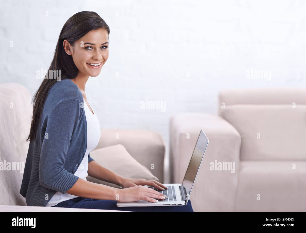 I can work from anywhere. A young woman working on her laptop at home ...