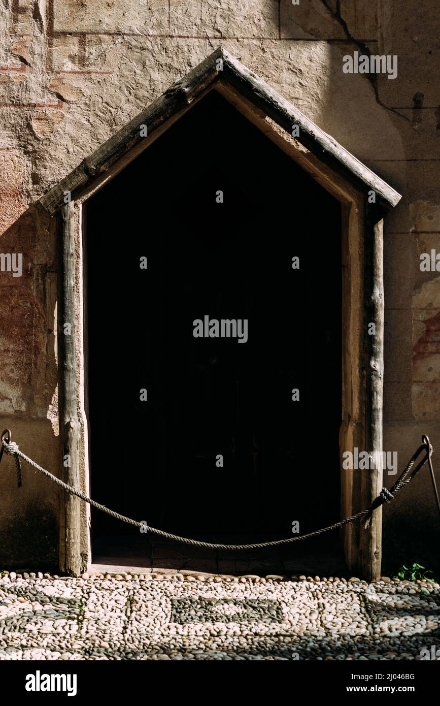 Vertical shot of an old medieval door with rope barrier and mosaic on ...