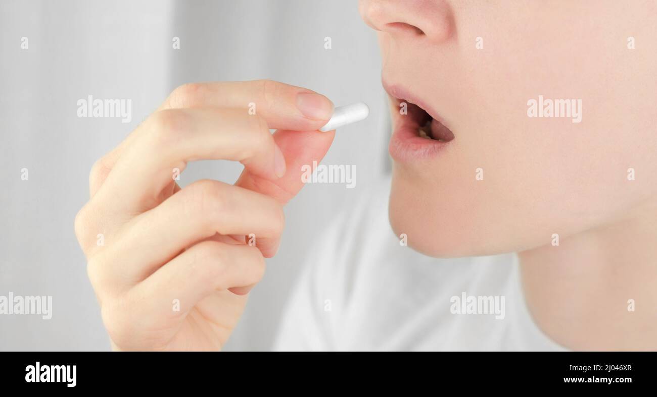 Close-up of a woman putting a pill into her mouth. Unrecognizable woman ...
