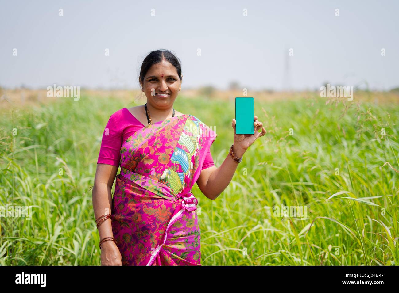 happy smiling Indian woman farmer showing green screen mobile phone in ...