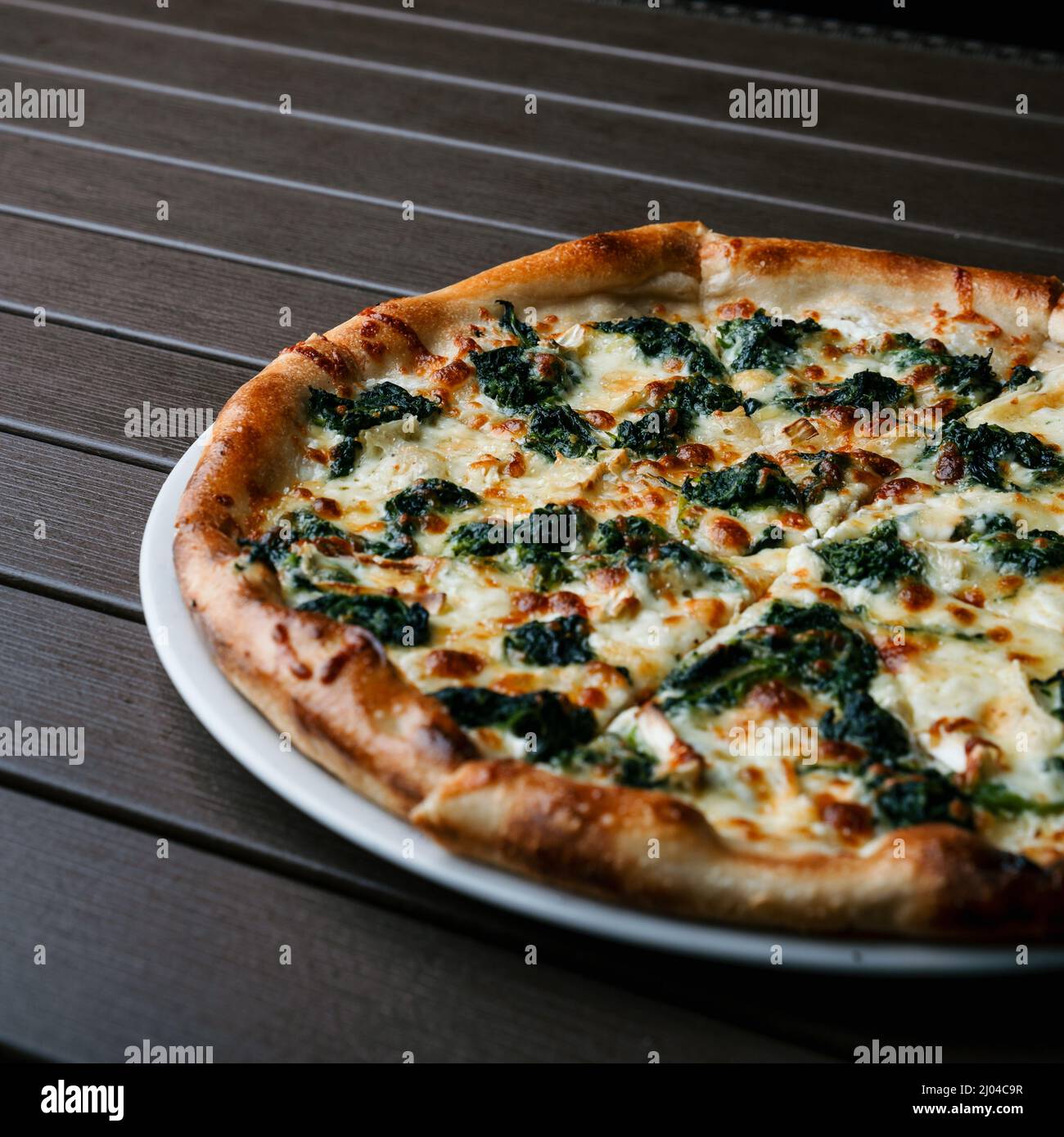 Serving of delicious fresh Italian pizza with spinach Stock Photo - Alamy
