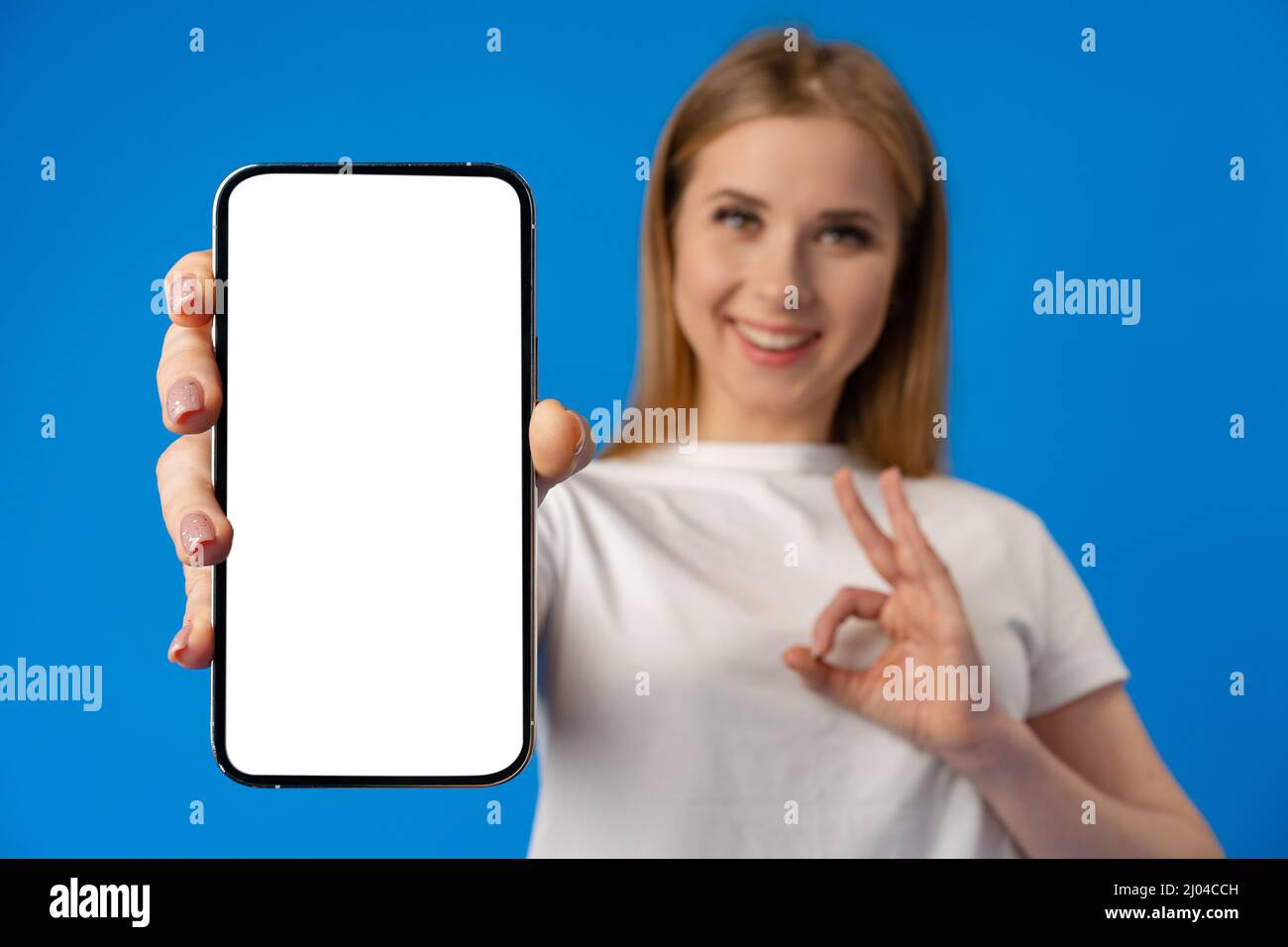 Young woman point finger at isolated smartphone screen over blue color ...