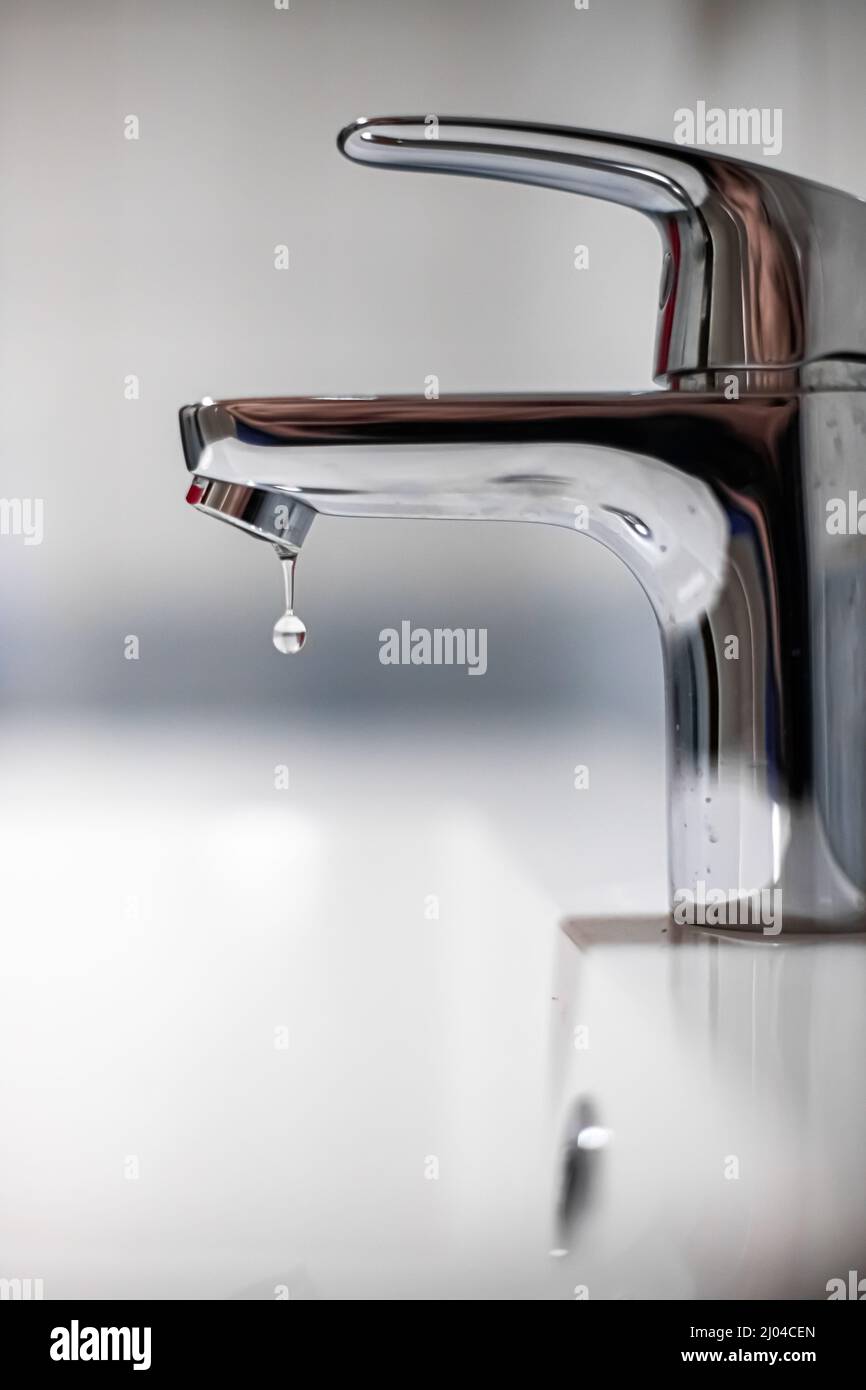 Vertical selective focus shot of a waterdrop dripping from a closed ...