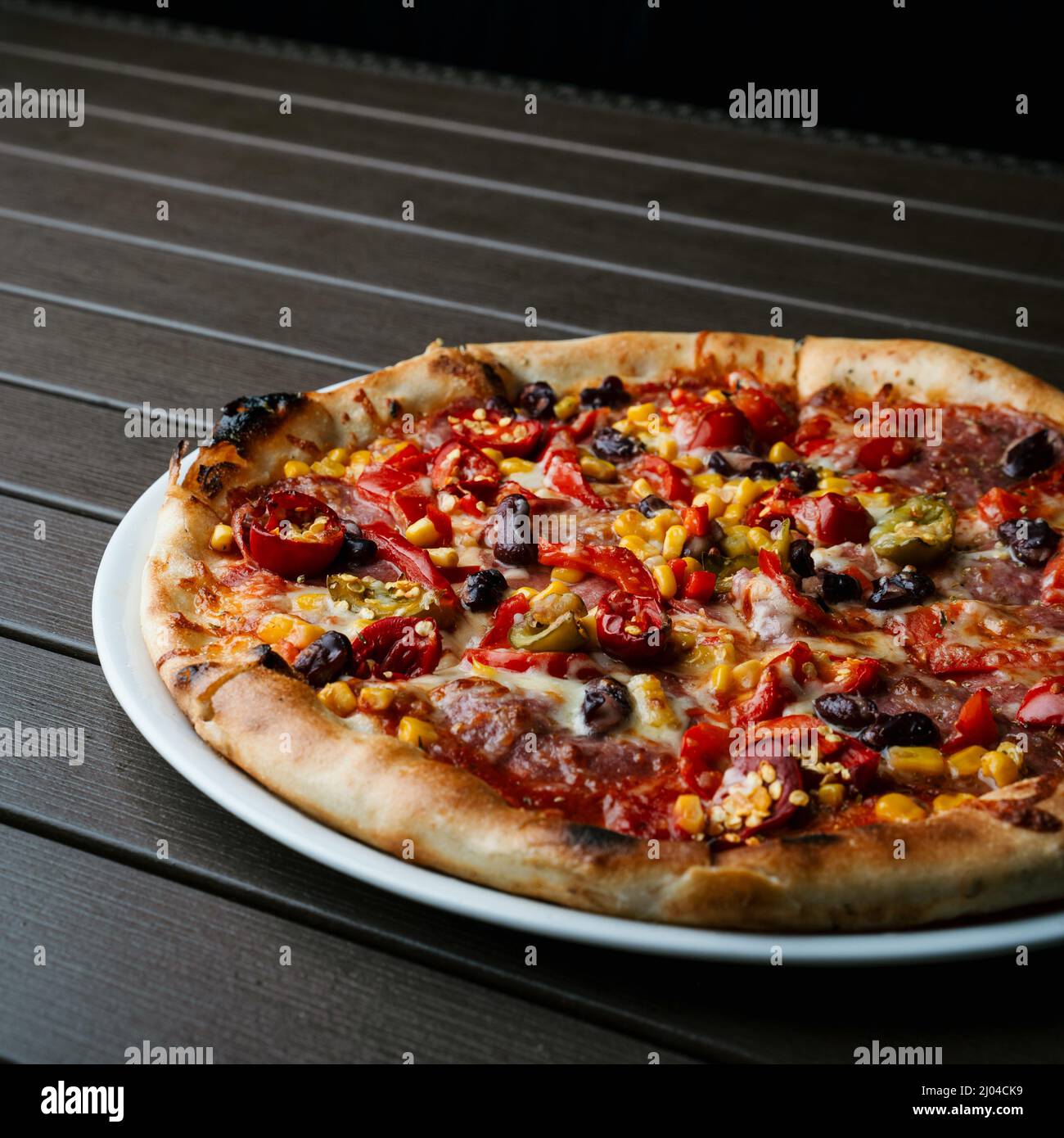 Serving of delicious fresh Italian pizza with oives, meat, corn, and ...