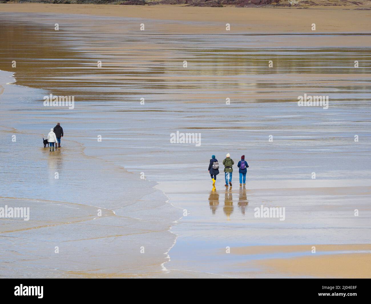 People walking on Polzeath Beach on a cold spring day, Cornwall, UK ...