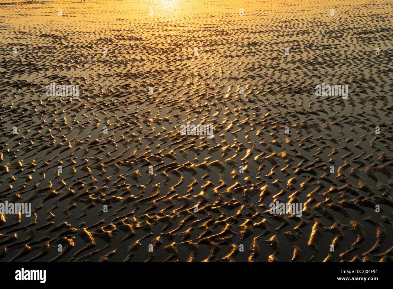The sandy beach at low tide shows ripples created by the receding water ...