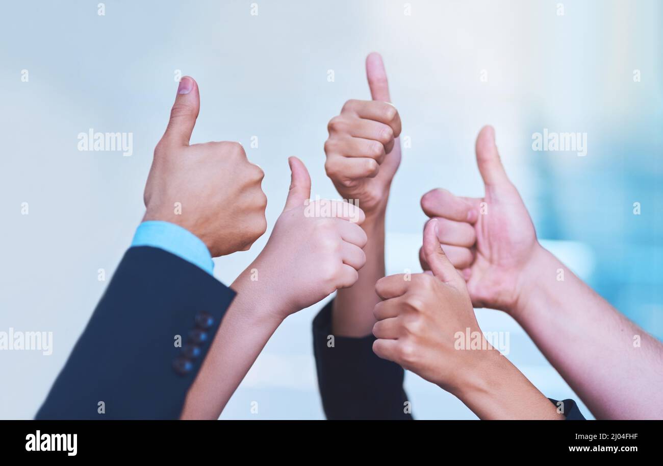 Well done. Shot of a group of office workers showing thumbs up together ...