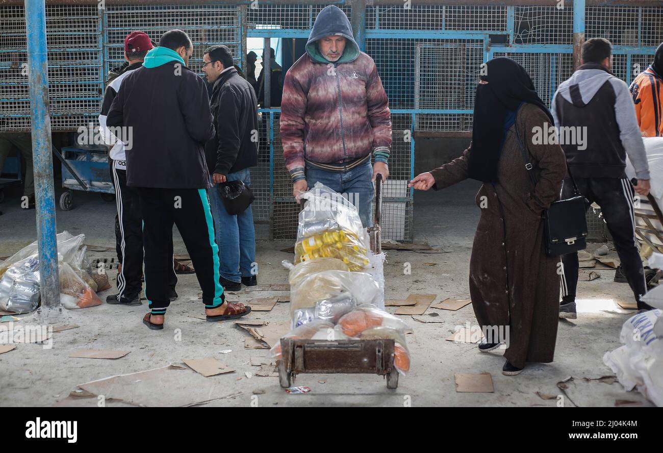 A Palestinian woman receives her food package from the UNRWA food aid ...