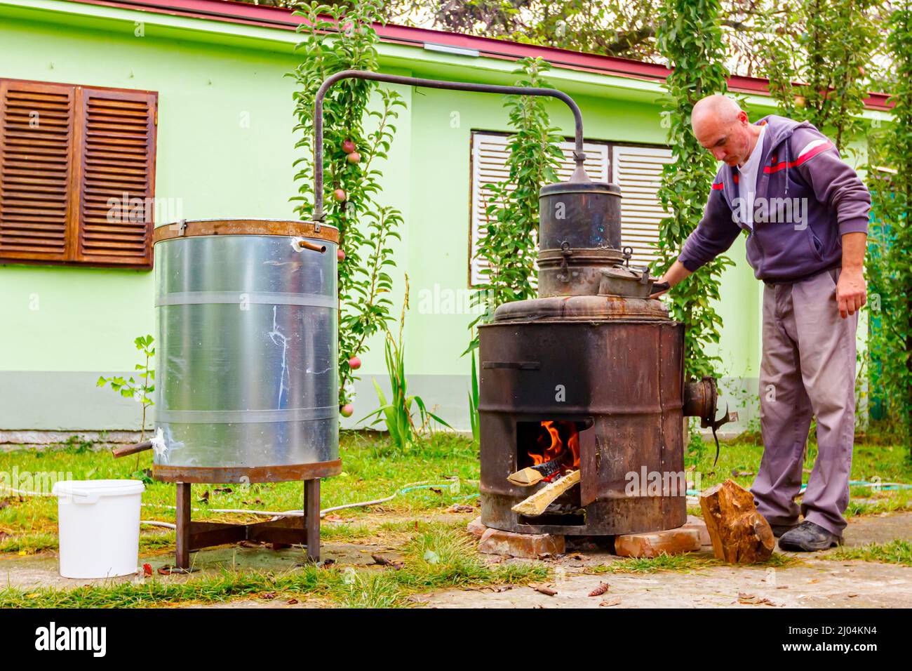 Man is manually turning lever to mix fruit marc in boiler of homemade ...