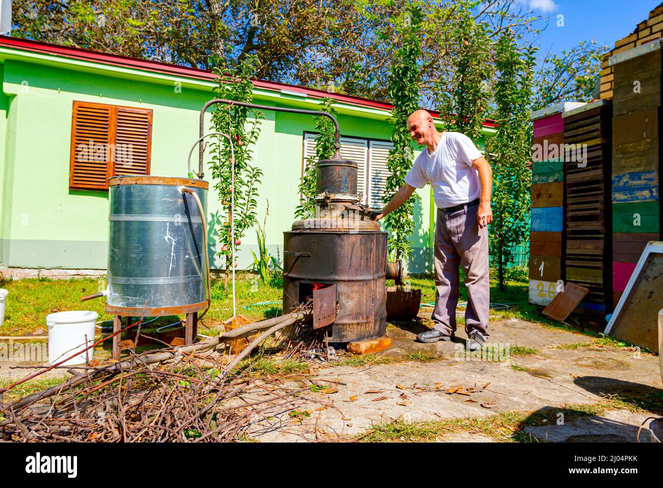 Man is manually turning lever to mix fruit marc in boiler of homemade ...