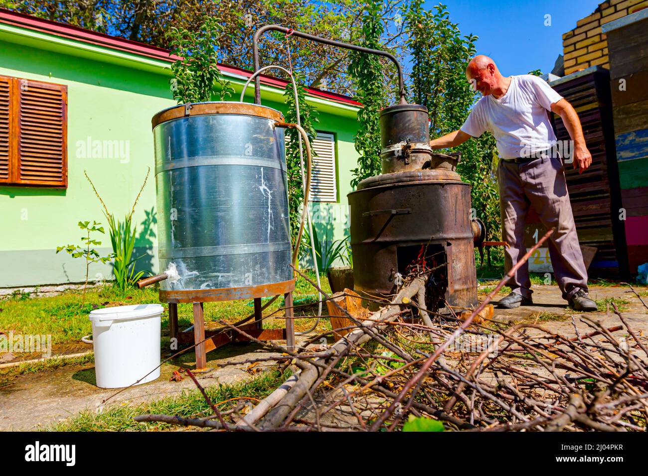 Man is manually turning lever to mix fruit marc in boiler of homemade ...