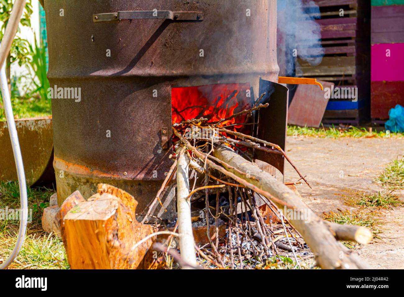 Fire burning in firebox of homemade distillery made of copper, making ...