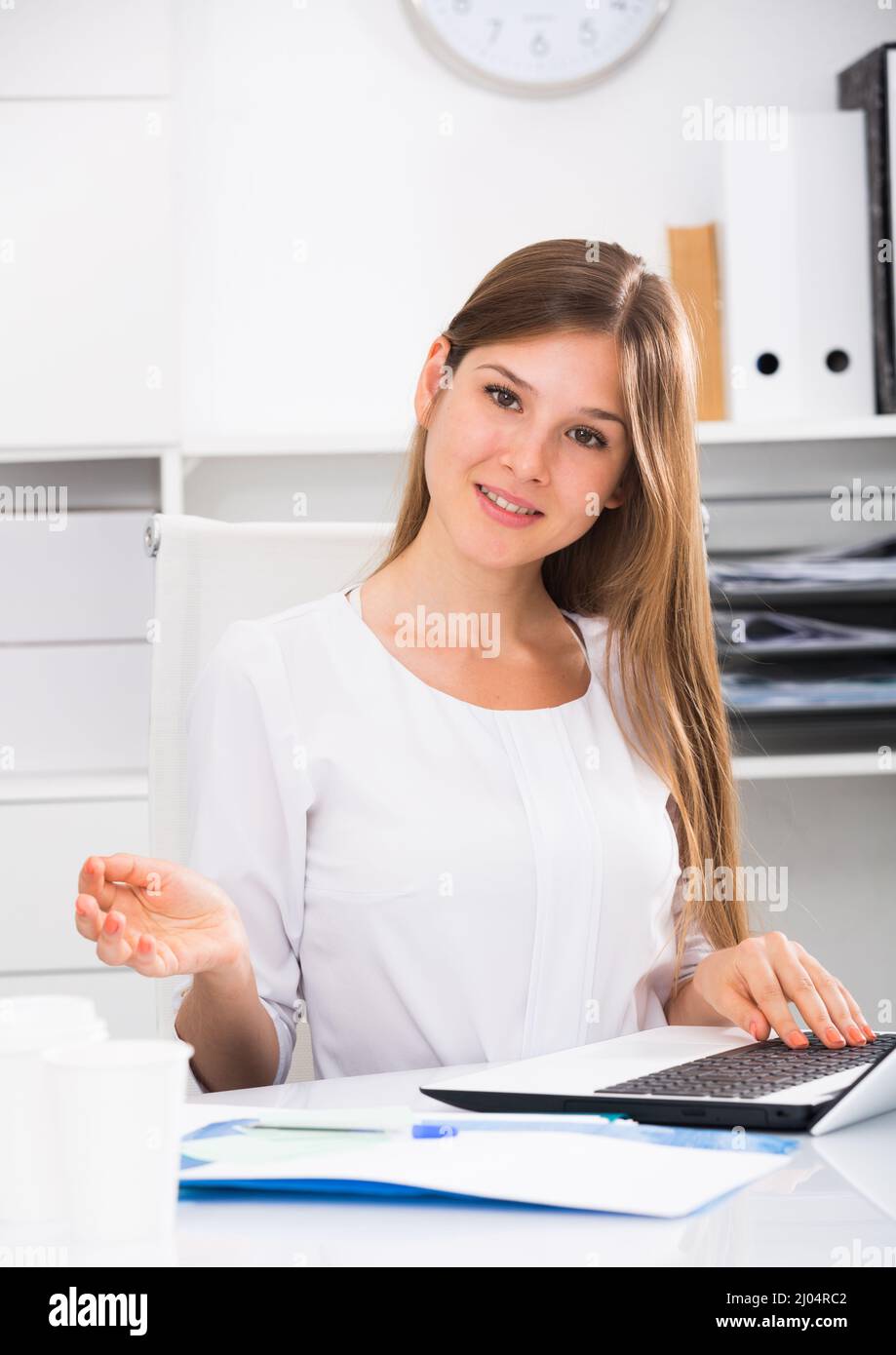 Attractive female office worker at workplace making welcome gesture ...