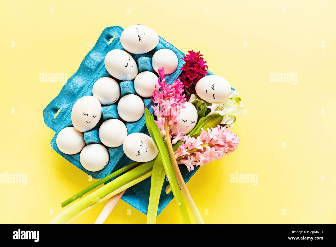 Creative easter eggs with cute face and sleepy eyes on pastel yellow ...