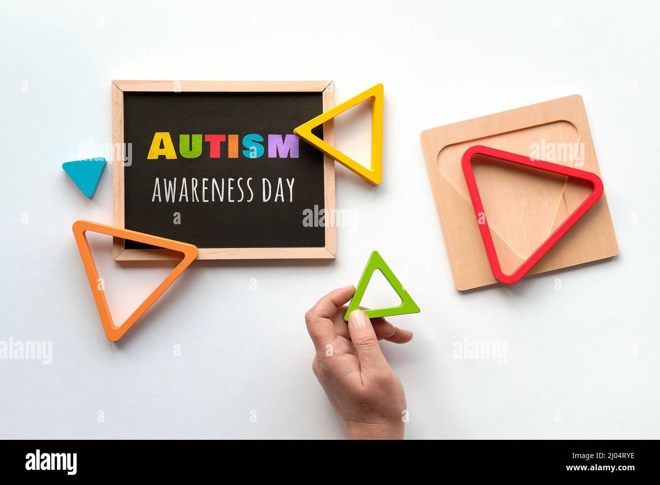 Text Autism awareness month on blackboard. Nested wood triangles in ...