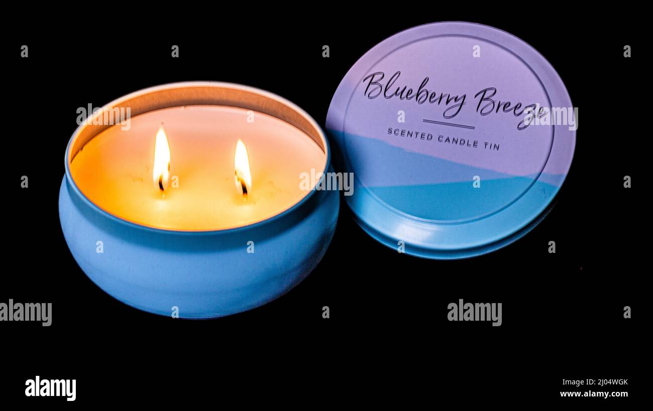 Blueberry breeze scented candle with flame burning in front of lid and ...