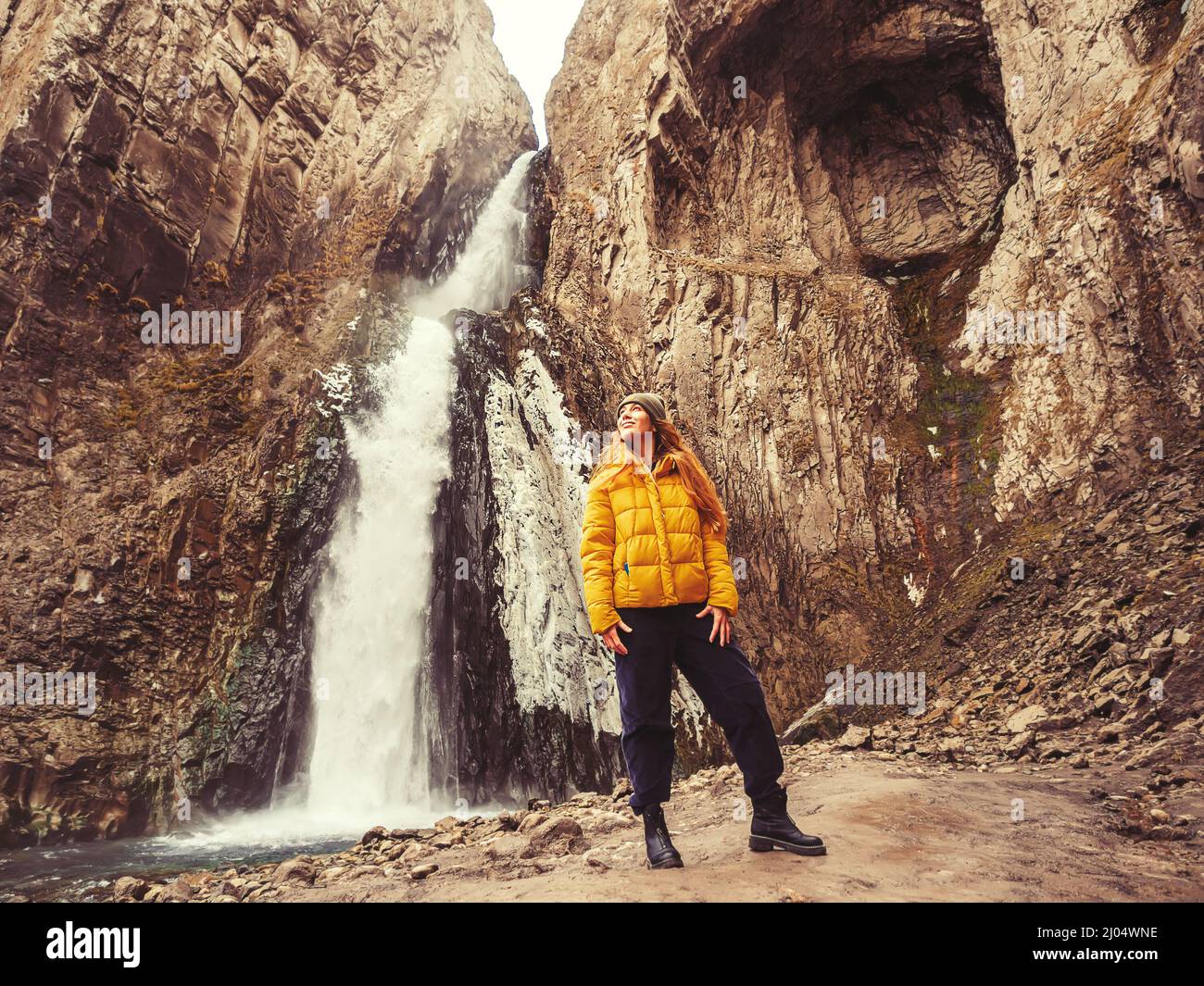 A woman looks up while standing against the background of icy stormy ...