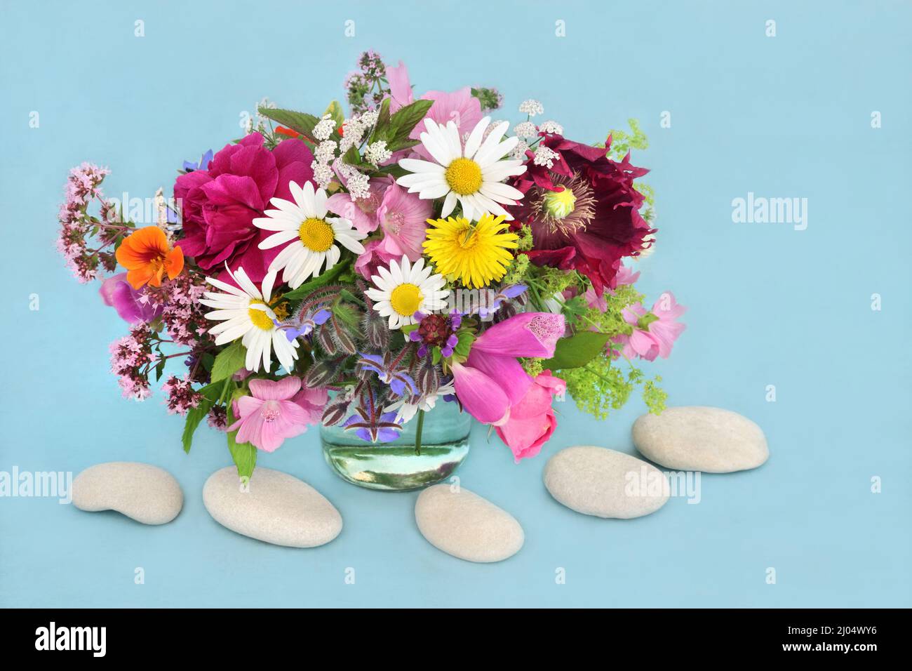 Summer flowers and herbs in a vase of with pebbles. All plants used in ...