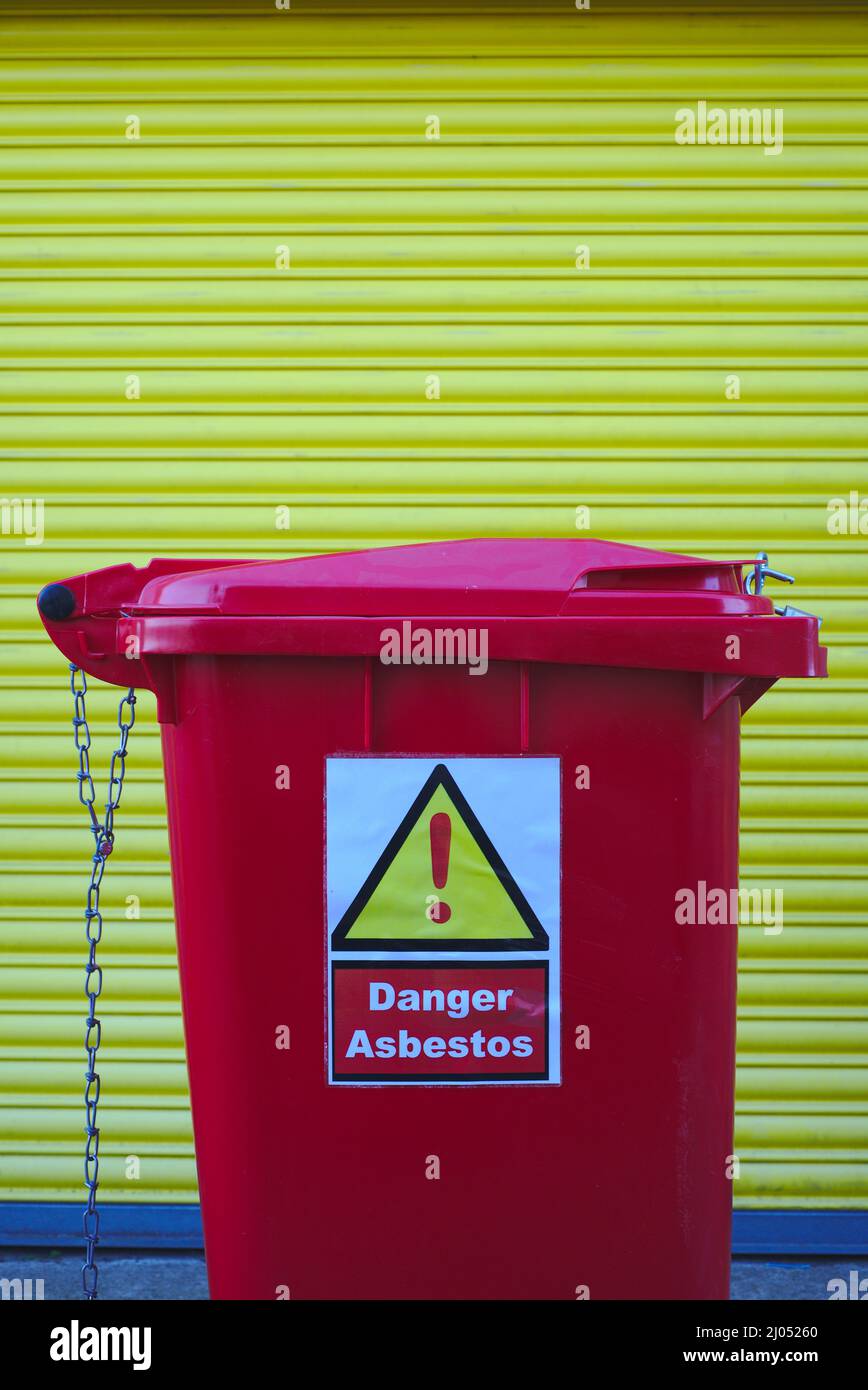 Red bin for collection of Asbestos waste marked with danger warning ...