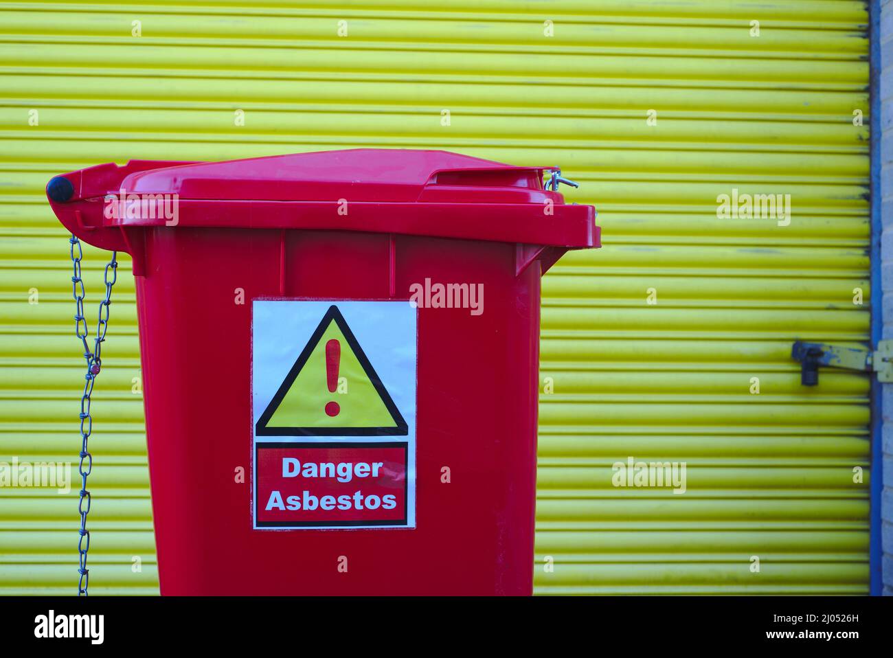 Red bin for collection of Asbestos waste marked with danger warning ...