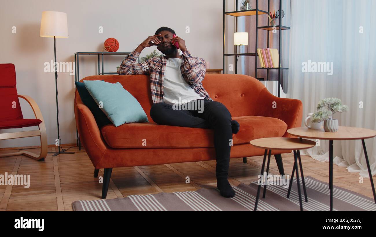 Portrait of tired sleepy man talking on mobile phone with friend making ...