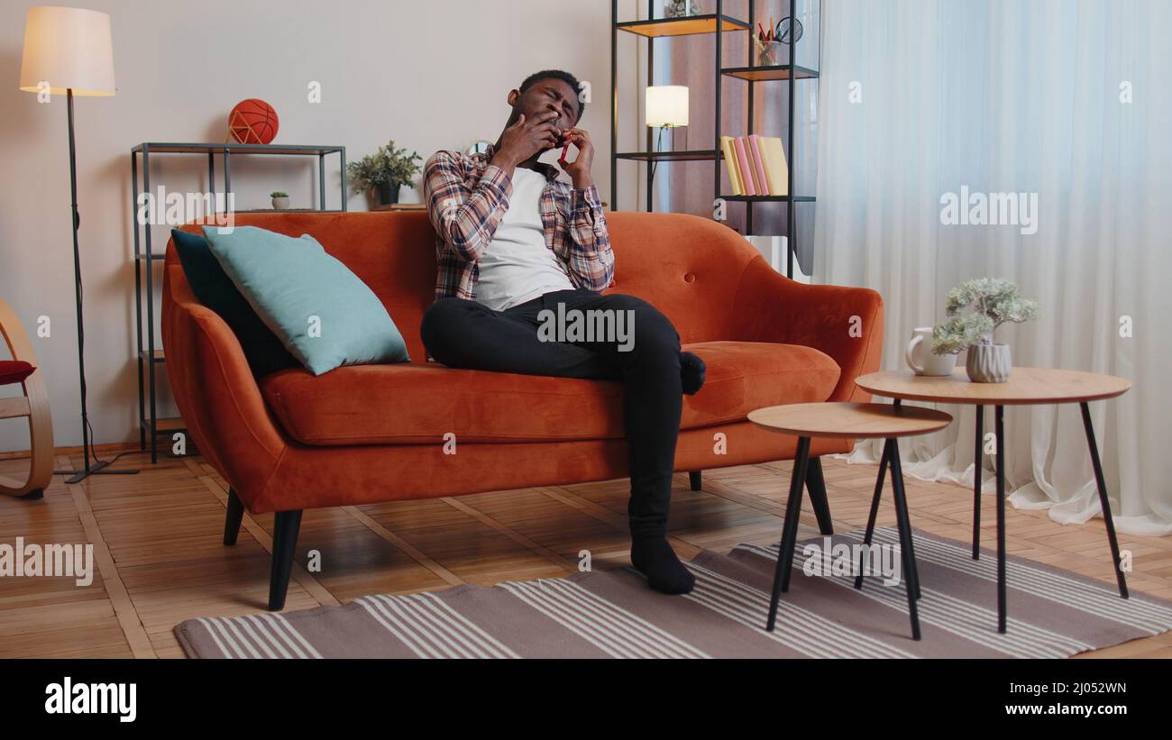 Portrait of tired sleepy man talking on mobile phone with friend making ...