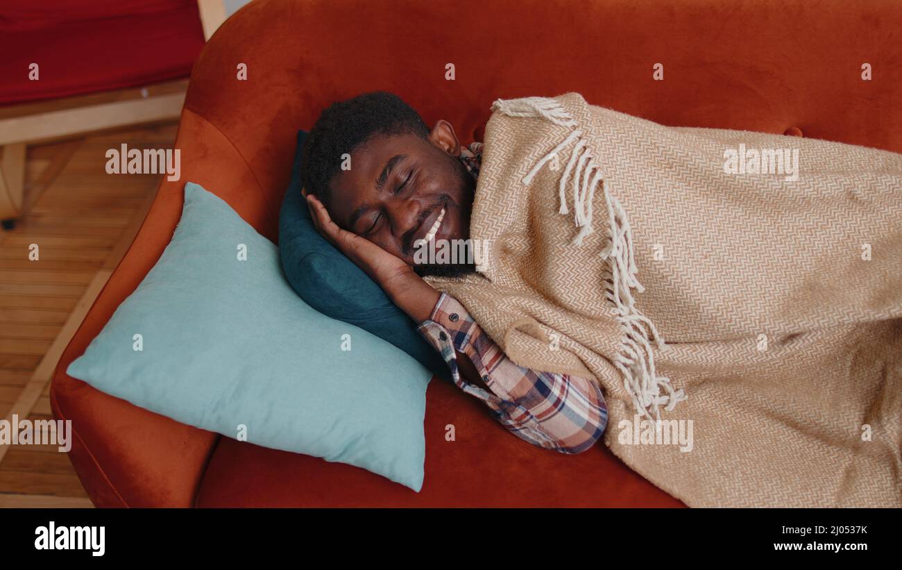 African american young man sleeping quietly in bedroom at home, smiling ...